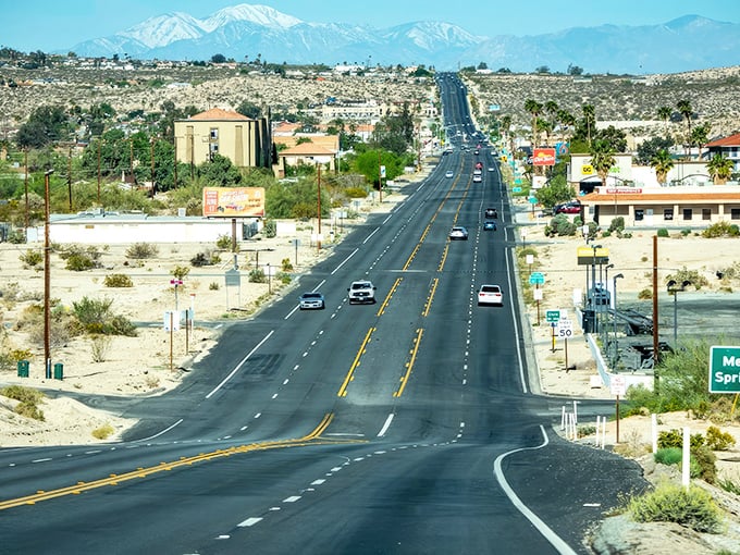 The road stretches toward snow-capped mountains, a reminder that desert living comes with spectacular views and the occasional need for a light jacket.