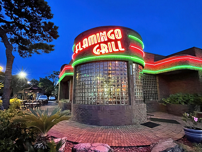The iconic neon-lit exterior of Flamingo Grill stands as a beacon of culinary promise, its distinctive glass block windows and brick fa&ccedil;ade hinting at the retro elegance within.