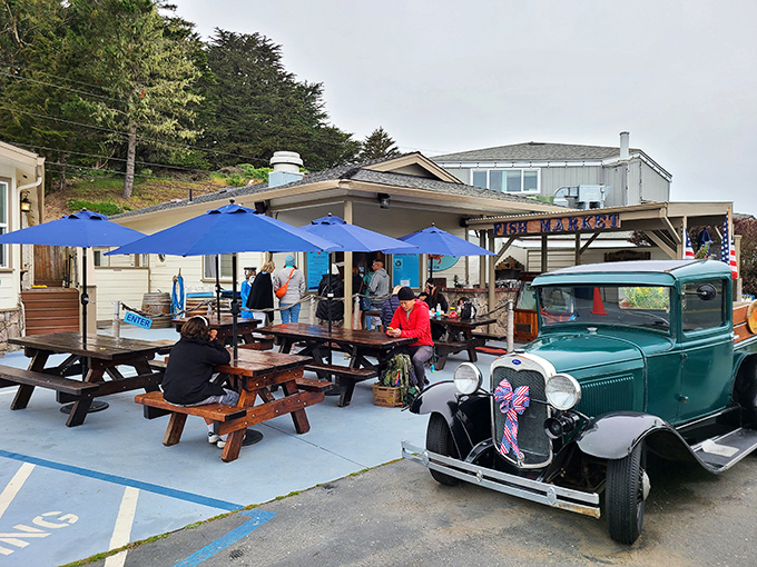 The unassuming exterior of Spud Point Crab Company, where blue umbrellas and wooden picnic tables promise seafood paradise. That vintage truck knows what's up.