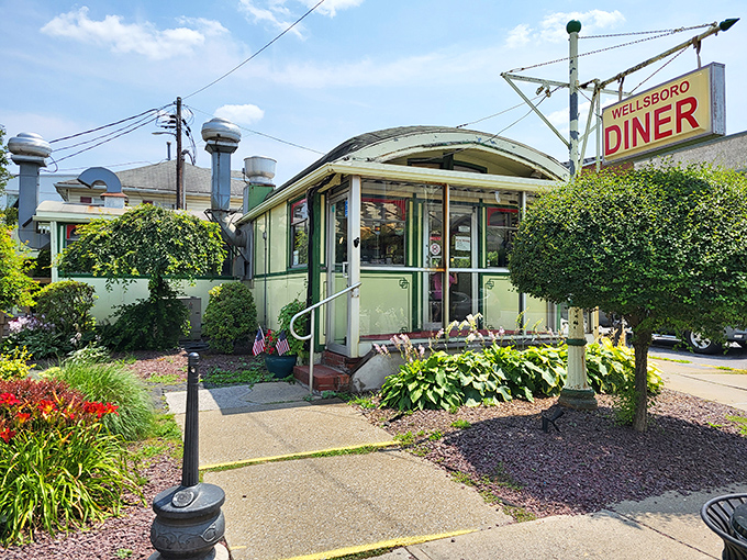 The mint-green exterior of Wellsboro Diner gleams like a time capsule on wheels, inviting hungry travelers with its classic barrel roof and nostalgic charm.