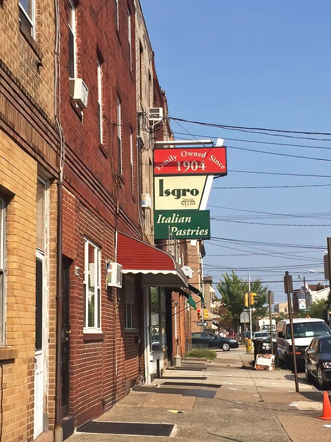The iconic red, cream, and green sign announcing Isgro's presence since 1904 - a beacon of sweetness on Christian Street's brick fa&ccedil;ade.