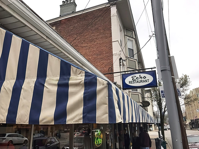 The iconic blue and white striped awning of The Echo stands as a beacon of breakfast hope on Hyde Park Square, promising culinary comfort beneath its vintage sign.