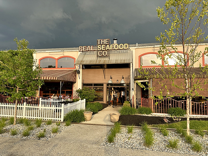 Storm clouds gather dramatically over The Real Seafood Co., as if nature itself is anticipating the flavor tsunami waiting inside.