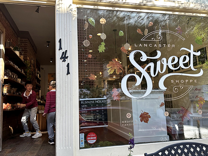 The storefront beckons like a lighthouse for sugar-seekers, with that glowing "Sweet" sign promising delicious refuge from the ordinary world outside.