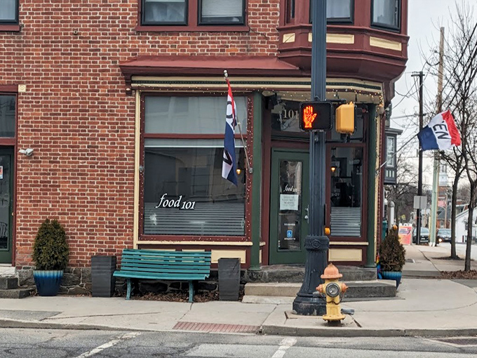 The charming exterior of Kitchen 101 beckons with its green door and vibrant flowers, like a culinary oasis on Chambersburg Street.