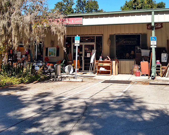 The unassuming entrance to Sugar Bear Antique Mall beckons with vintage charm. Green posts, potted plants, and a welcoming porch hint at treasures waiting just inside.