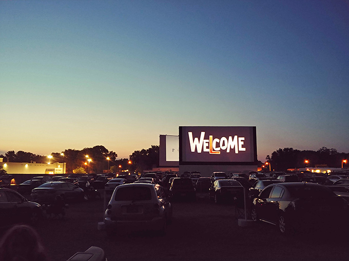 Twilight magic unfolds as the massive screen welcomes moviegoers. Nothing says summer nostalgia quite like cars gathered under a darkening sky.