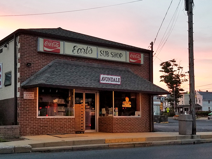 Earl's Sub Shop at sunset &ndash; where the humble brick exterior and vintage Coca-Cola signs promise authentic deliciousness that transcends the modest surroundings.