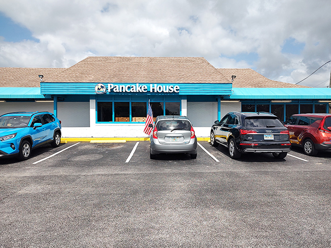 The cheerful blue facade of My Island Pancake House stands proudly against Florida's sky, American flag waving a warm welcome to hungry visitors.