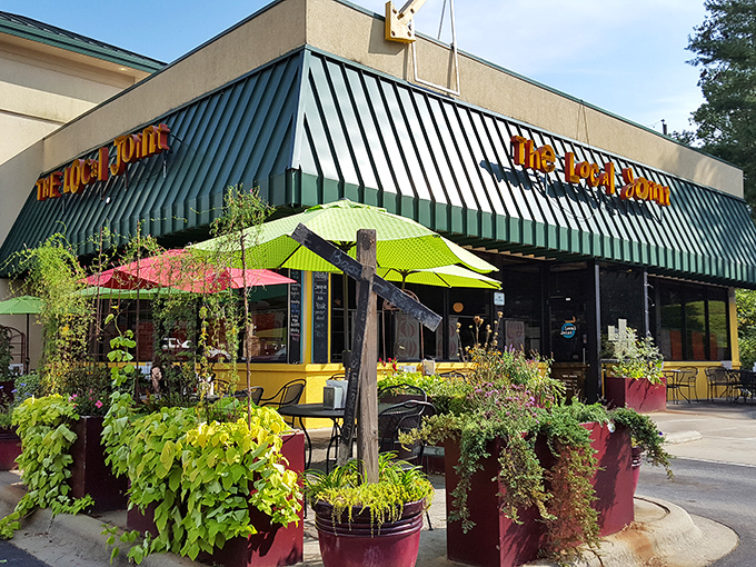 The cheerful yellow exterior with vibrant red planters says "happiness served here" before you even walk through the door.