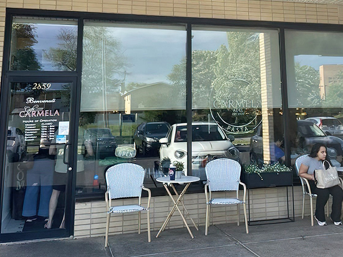 The unassuming storefront of Café Carmela beckons with European charm. Those white bistro chairs aren't just for show—they're waiting for you.