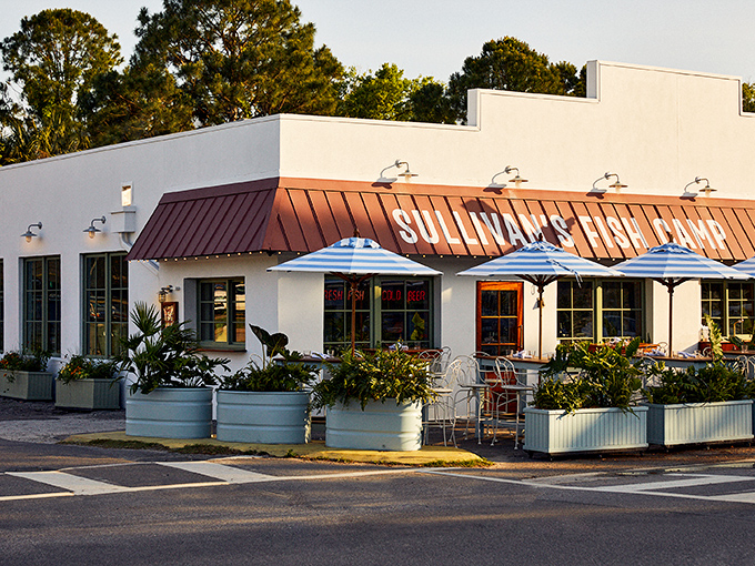 Sullivan's Fish Camp welcomes hungry seafood seekers with its cheerful white exterior, copper-colored roof, and those inviting blue umbrellas promising shade and satisfaction.