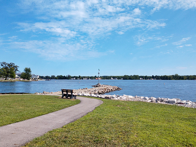 A perfect Ohio afternoon unfolds at Buckeye Lake, where a solitary bench invites contemplation along the rocky shoreline. Nature's therapy session, no appointment necessary.