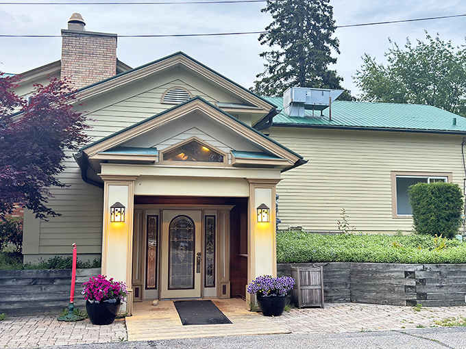 The welcoming facade of The Grill House beckons like an old friend, promising culinary delights behind its cream-colored exterior and flower-adorned entrance.