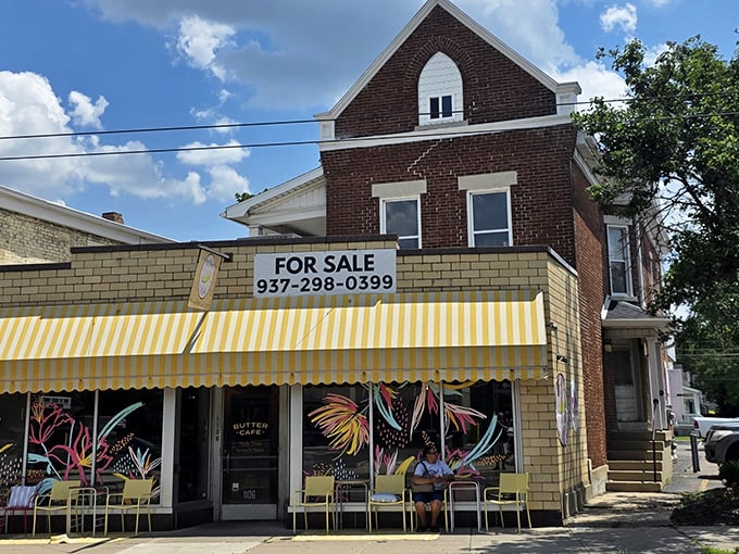 The cheerful yellow-striped awning of Butter Cafe stands out like a breakfast beacon on Brown Street, with vibrant murals promising colorful culinary adventures inside.