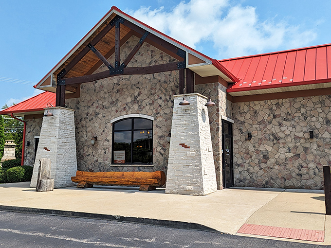 Stone and timber meet red metal roofing in this rustic-modern haven. The wooden bench outside practically whispers, "Stay awhile, friend."