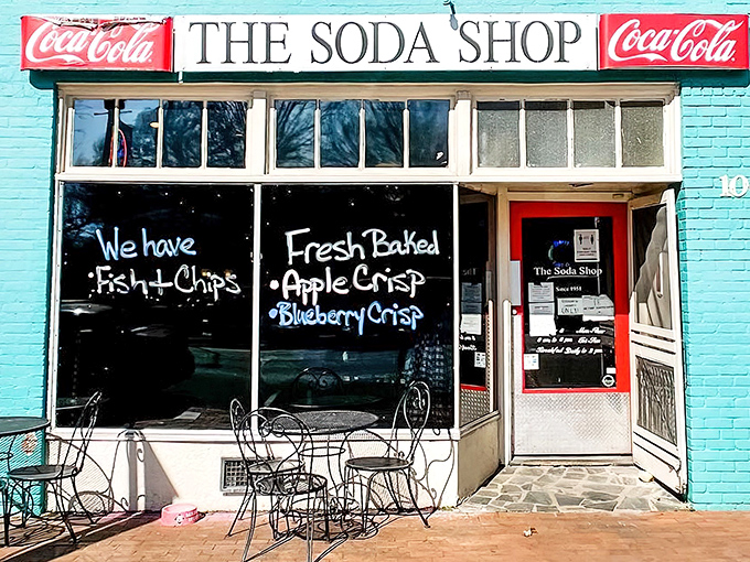 The turquoise facade of The Soda Shop stands like a portal to simpler times, complete with handwritten window promises of fish & chips and fresh-baked treats.