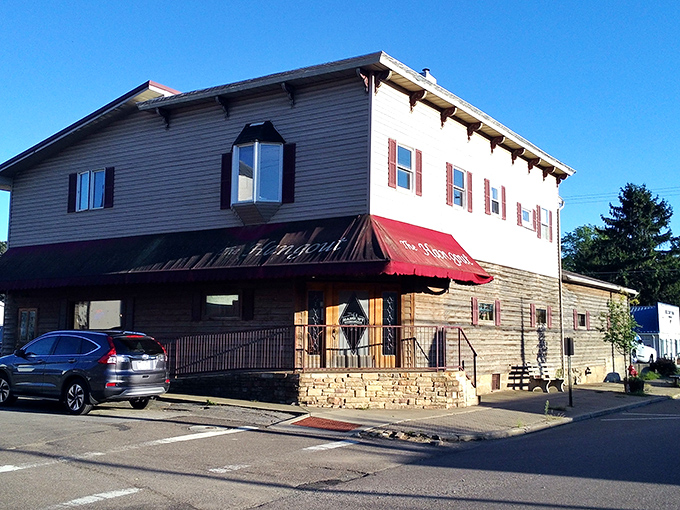 The Hangout's welcoming facade with its burgundy awning and hanging flower baskets promises small-town charm before you even step through the door.