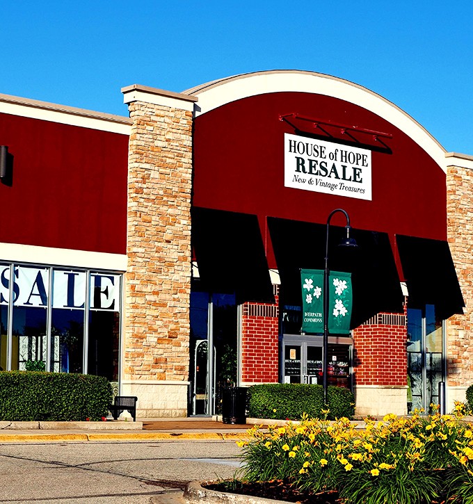 The welcoming facade of House of Hope Resale stands out with its distinctive red awning and stone accents&mdash;retail therapy with a conscience awaits inside.