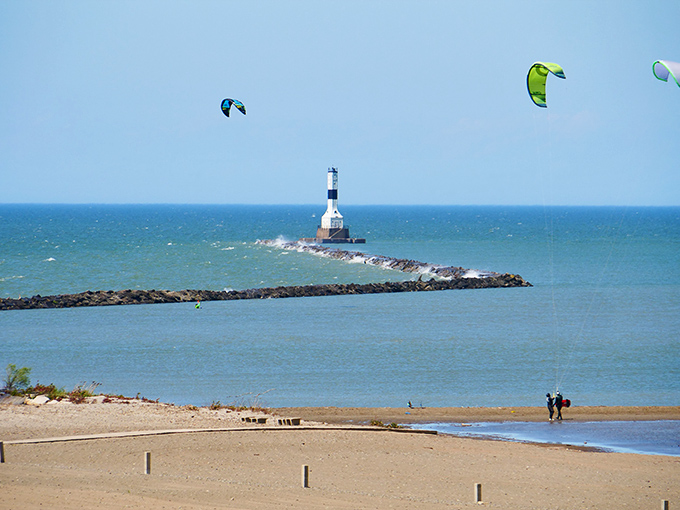 The iconic lighthouse stands sentinel at the end of the breakwall, while colorful kites dance above Lake Erie's surprisingly Caribbean-blue waters.