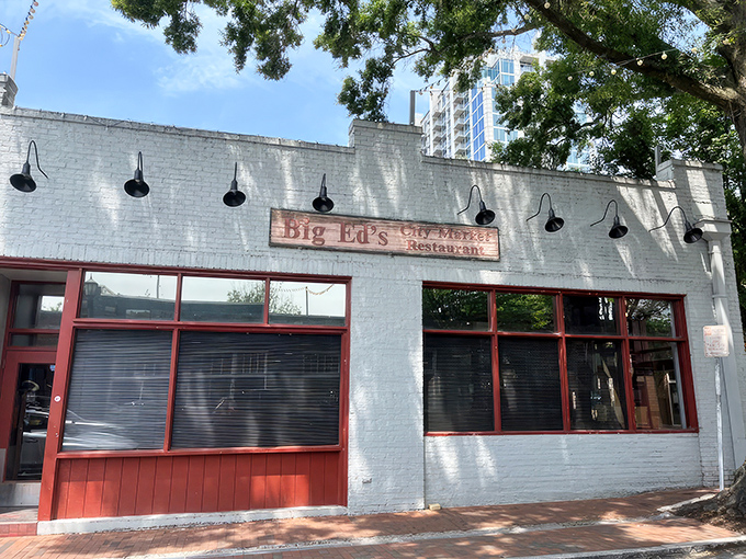 The unassuming white brick exterior of Big Ed's City Market Restaurant, where culinary magic happens behind those red-trimmed windows.
