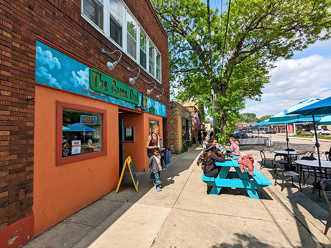 The vibrant turquoise storefront of The Green Owl Cafe brightens Atwood Avenue like a tropical bird in Wisconsin's urban landscape.