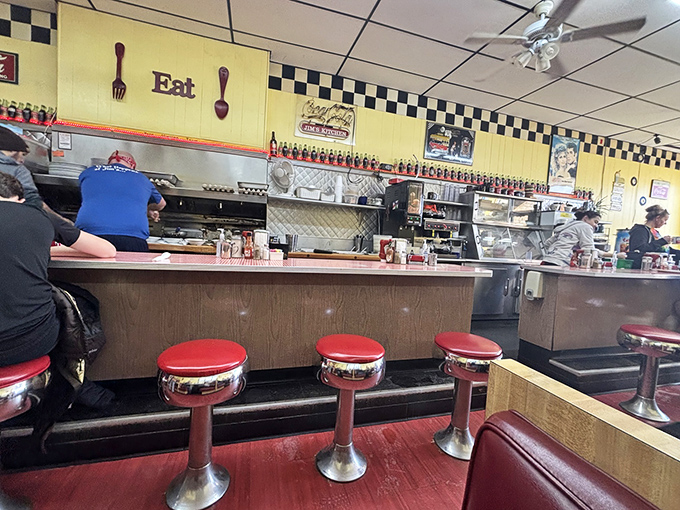 The classic diner counter setup where every seat offers front-row tickets to the culinary show.