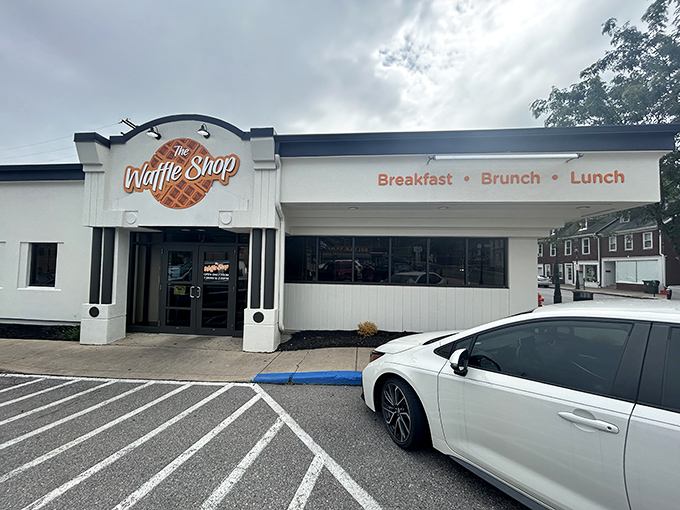 The unassuming white exterior of The Waffle Shop beckons with its simple orange waffle logo—proof that the best breakfast spots don't need flashy facades to deliver morning magic.