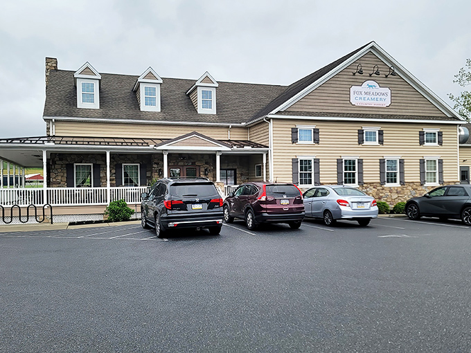 The farmhouse-style exterior of Fox Meadows Creamery welcomes visitors with its stone facade and inviting wraparound porch&mdash;architectural proof that calories consumed on rocking chairs don't count.
