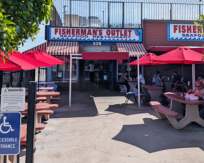 The red umbrellas at Fisherman's Outlet beckon like maritime flags signaling "fresh seafood ahead." This unassuming storefront hides treasures that would make Neptune himself line up.