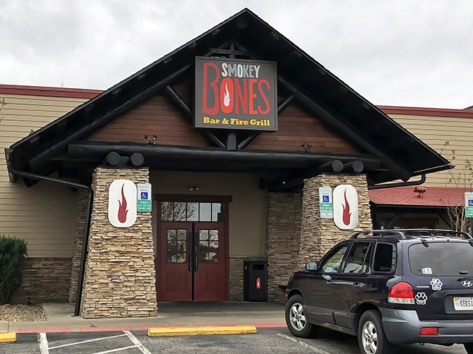 The rustic lodge-style exterior of Smokey Bones beckons meat lovers with its stone facade and distinctive peaked roof.