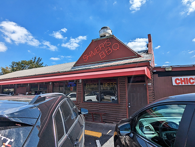 The log cabin exterior with its bright red roof isn't trying to impress anyone—it's too busy smoking some of Florida's best barbecue.