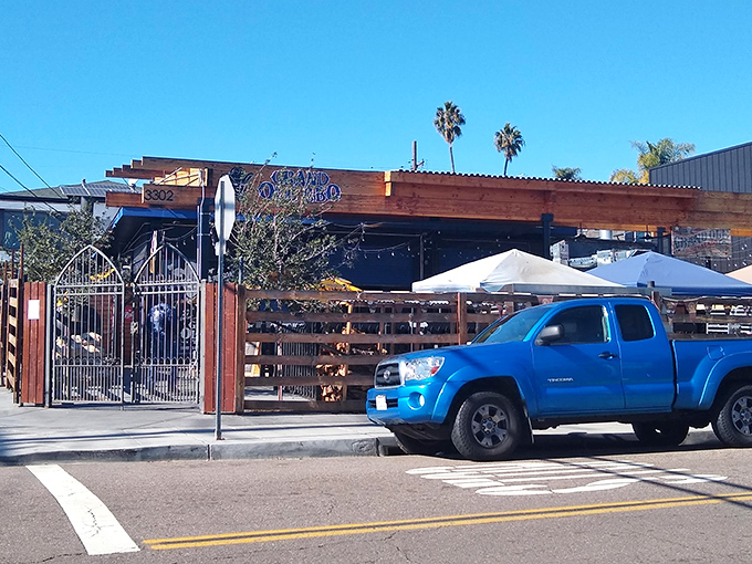 The rustic wooden facade of Grand Ole BBQ beckons like a smoke signal to barbecue pilgrims. Those yellow umbrellas aren't just for show&mdash;they're holding space for your BBQ dreams.