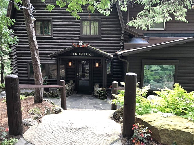 Nature doesn't just surround Ishnala—it embraces it. This log cabin entrance, nestled among towering pines, promises wilderness luxury before you even step inside.