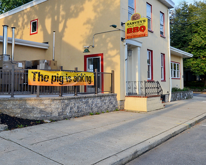 The bright yellow exterior of Harvey's Main Street BBQ announces itself with a banner that doesn't mince words: "The pig is cooking." Truth in advertising at its finest!