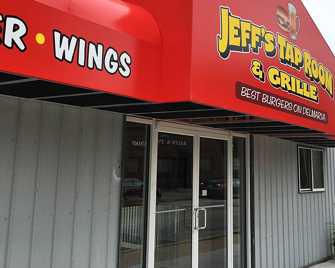 The bright red awning of Jeff's Taproom & Grille stands out like a culinary lighthouse, beckoning hungry travelers with promises of Delmarva's best burgers.