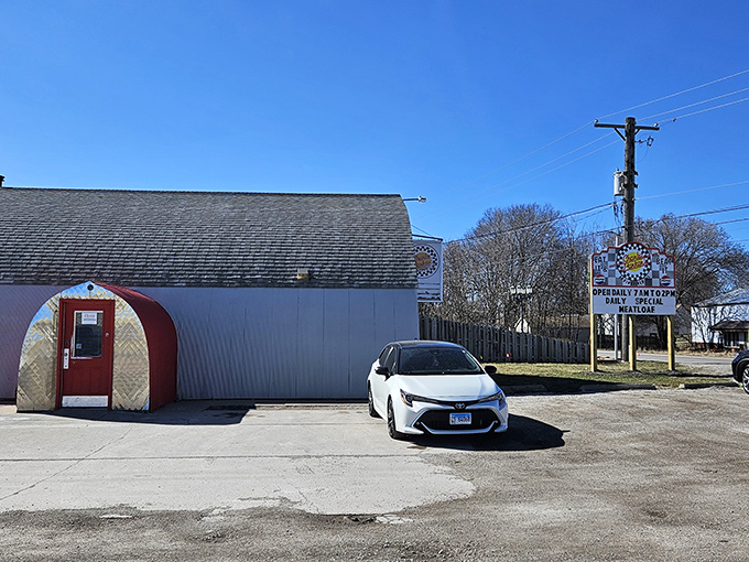 The unassuming Quonset hut exterior of Charlie Parker's Diner stands as a time capsule from post-WWII America, complete with that iconic red door beckoning hungry travelers.