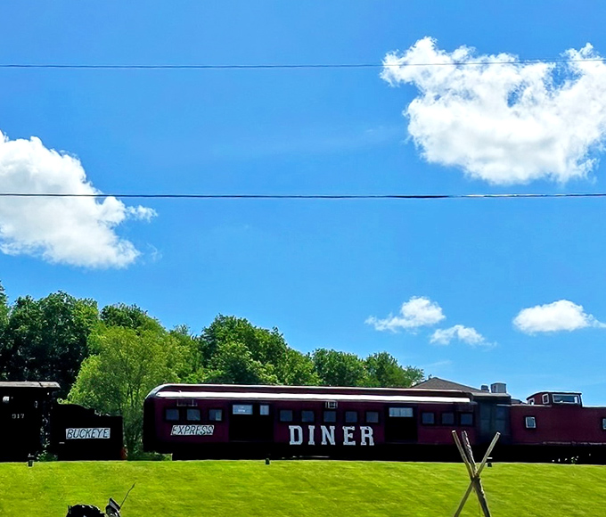All aboard the flavor express! The Buckeye Express Diner stands proudly against Ohio's blue sky, a crimson beacon for hungry travelers seeking culinary adventure.