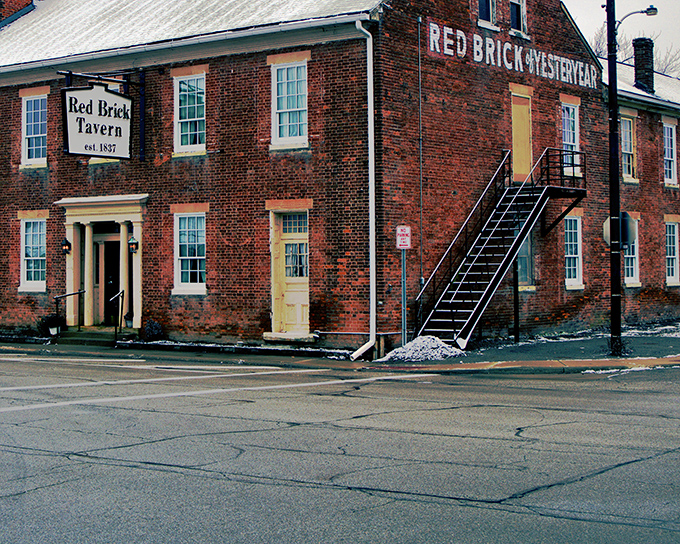 The historic Red Brick Tavern stands proudly since 1837, its weathered facade a testament to nearly two centuries of welcoming hungry travelers along the National Road. 