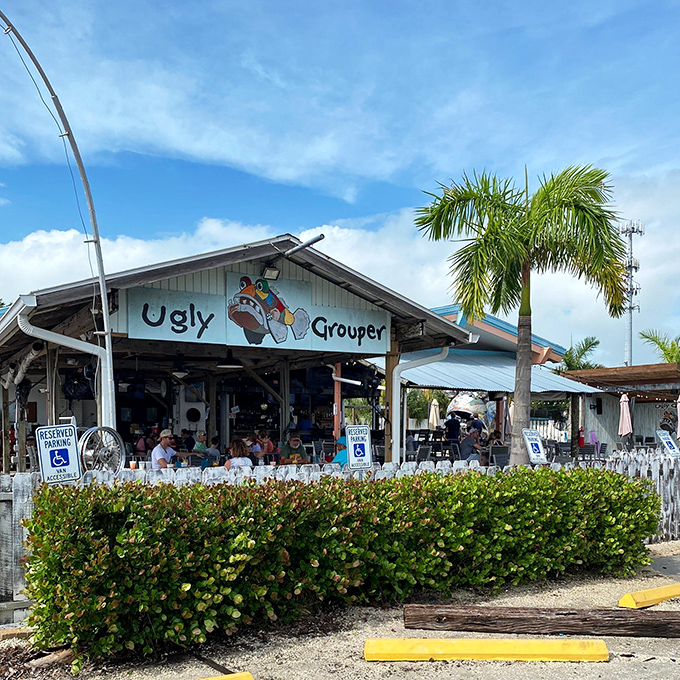 The colorful facade of The Ugly Grouper welcomes visitors with its whimsical cartoon mascot, promising a laid-back Florida dining experience unlike any other.