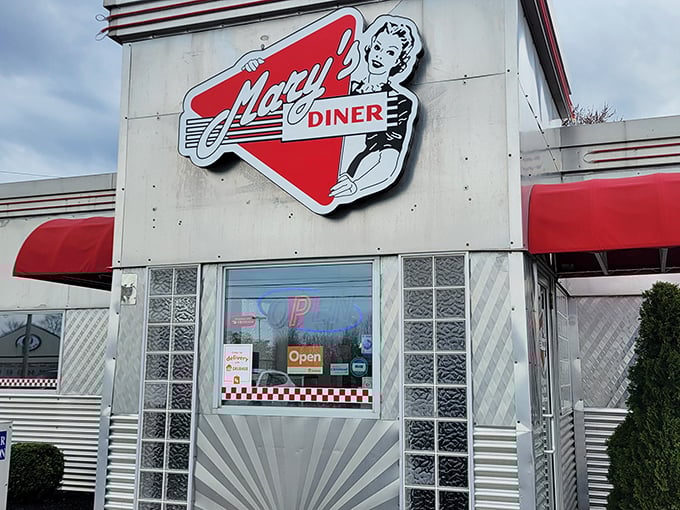 The iconic red triangle sign of Mary's Diner beckons hungry travelers like a neon lighthouse guiding ships to breakfast harbor.