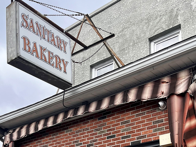 The iconic Sanitary Bakery sign hangs proudly above the brick storefront, promising cleanliness and deliciousness in equal measure.