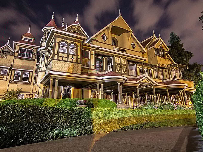 The Winchester Mystery House glows with eerie elegance at night, its Victorian fa&ccedil;ade hiding architectural oddities that would make M.C. Escher scratch his head in confusion.