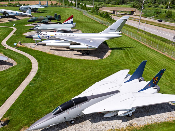 A bird's-eye view of aviation history where massive war birds rest on manicured lawns like metallic sculptures waiting for their next mission. 