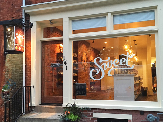 The storefront beckons like a lighthouse for sugar-seekers, with that glowing "Sweet" sign promising delicious refuge from the ordinary world outside.