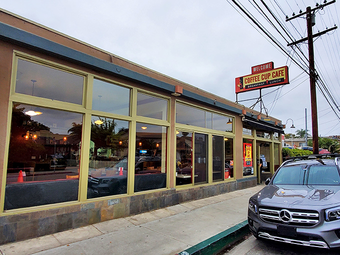 The unassuming exterior hides breakfast greatness like a superhero's secret identity. Blue trim, large windows, and a vintage sign promising morning salvation.
