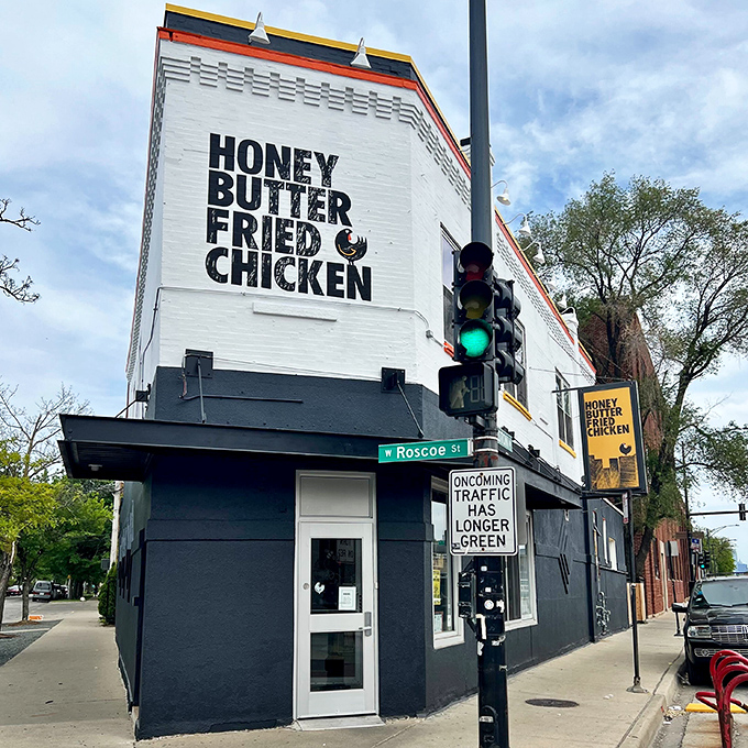 The corner building announces its purpose without pretense. Bold lettering on white brick promises a straightforward mission: chicken that will change your life.