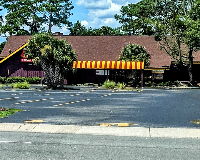 Chuck's exterior stands as a time capsule of steakhouse tradition, with its distinctive red-brown siding and cheerful yellow-striped awning beckoning hungry travelers.