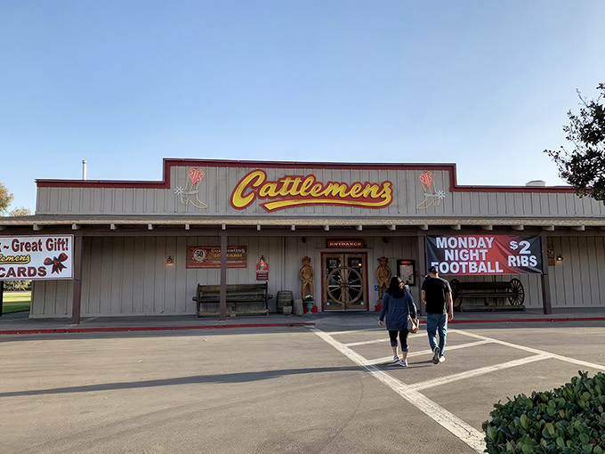 The iconic yellow Cattlemens sign welcomes hungry travelers like a beacon of beef-related bliss. Those wooden cowboys aren't just decorative&mdash;they're promising you the steak of your dreams.