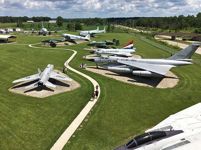 A bird's-eye view of aviation history where massive war birds rest on manicured lawns like metallic sculptures waiting for their next mission. 